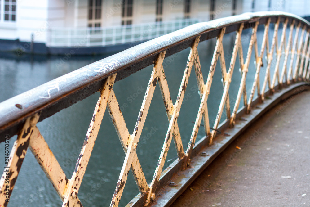 Metal railing of a pedestrian bridge in Camden, London, with cracked ...