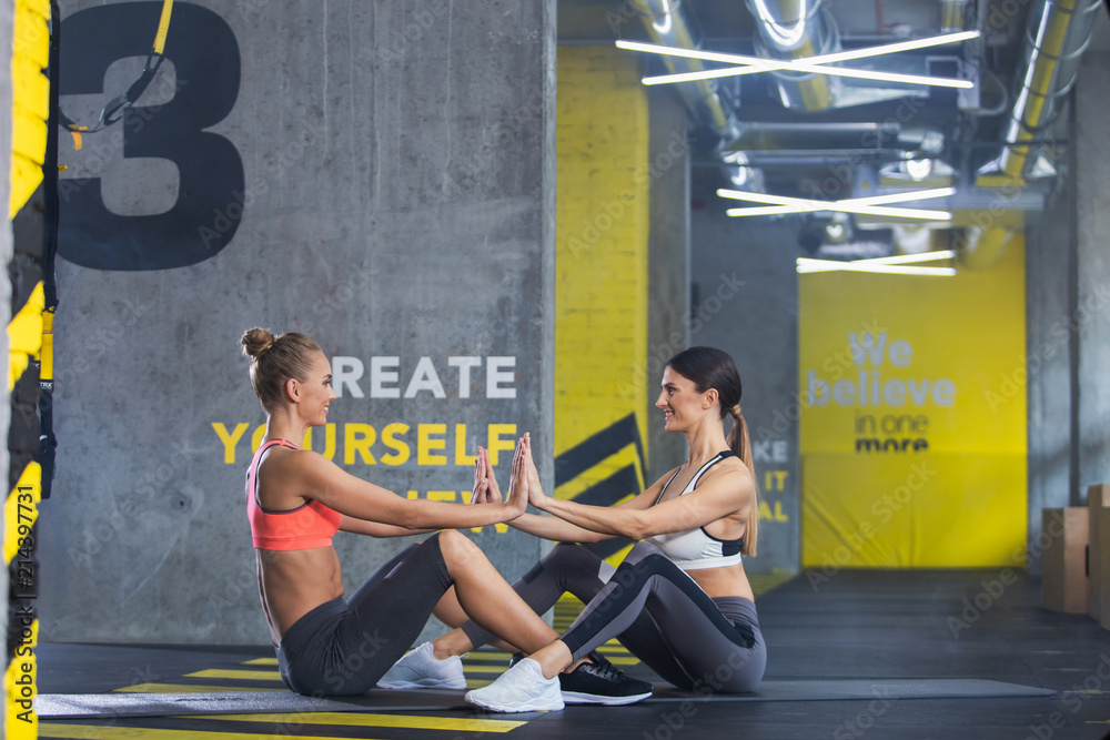 Delighted athletic girls are enjoying training together in fitness club ...