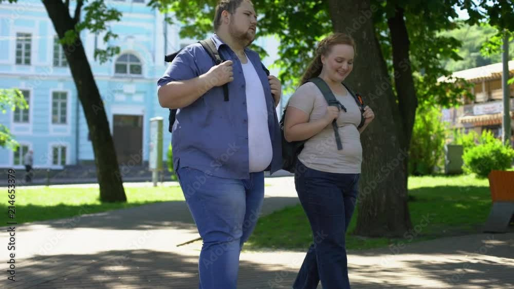 Student male and female walking in campus park, flirting on date, fat ...