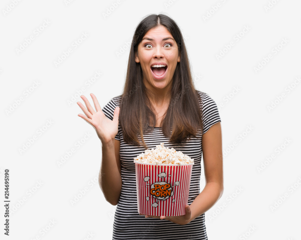 Young beautiful hispanic eating popcorn very happy and excited, winner ...
