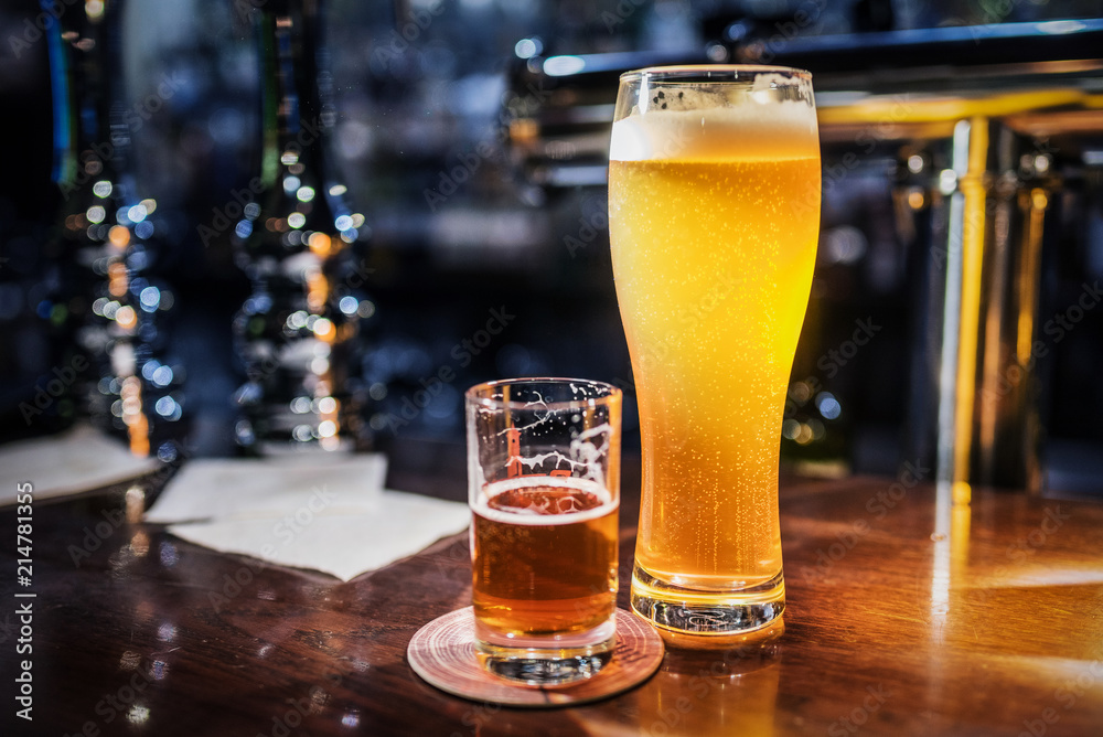 Light beer in a beer glass and dark beer in a small glass lighted with ...