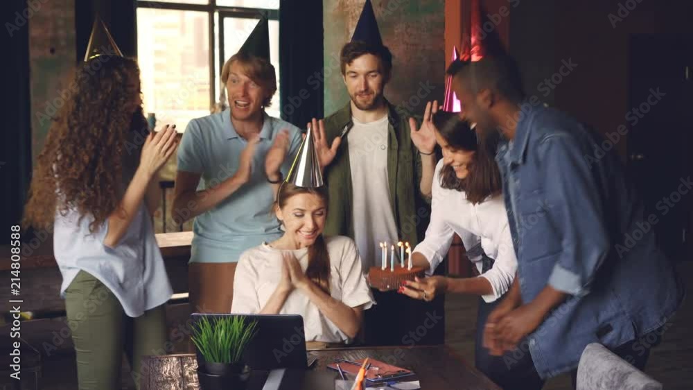 Cheerful girl office worker is working at desk while her coworkers are ...