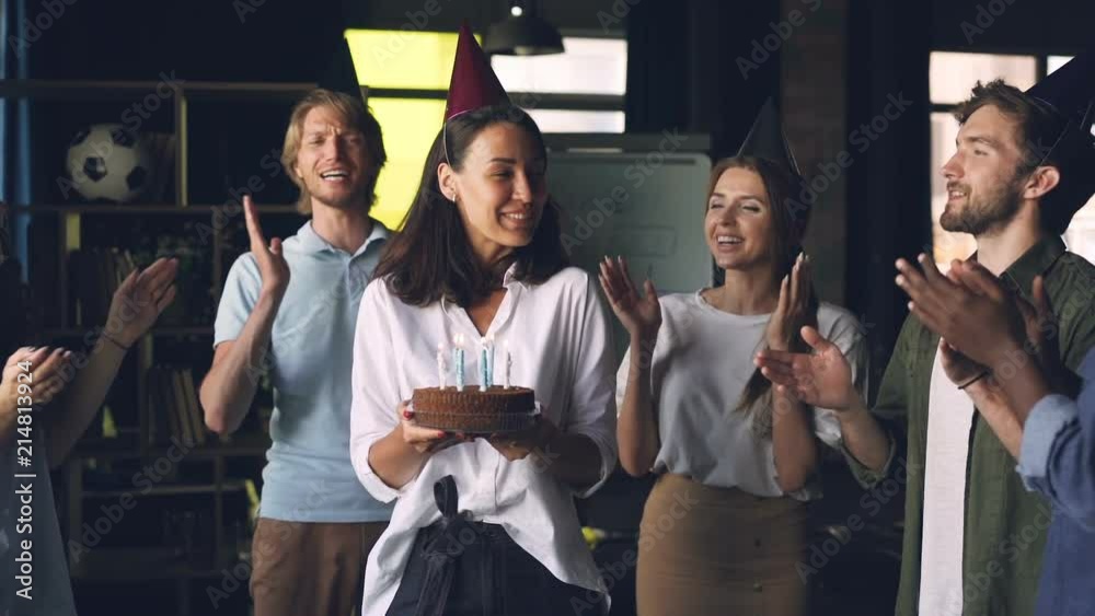 Slow motion of happy young lady holding birthday cake and blowing ...