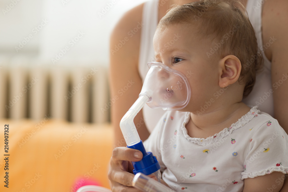 Baby taking respiratory inhalation therapy. Mother holding the mask of ...
