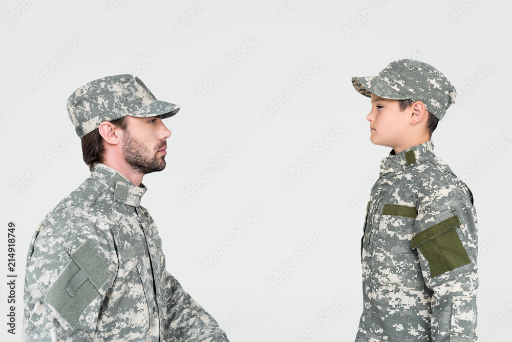 side view of soldier and son in military uniforms looking at each other ...