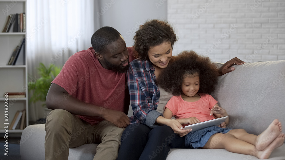 Parents watching their little daughter learning educational app on ...