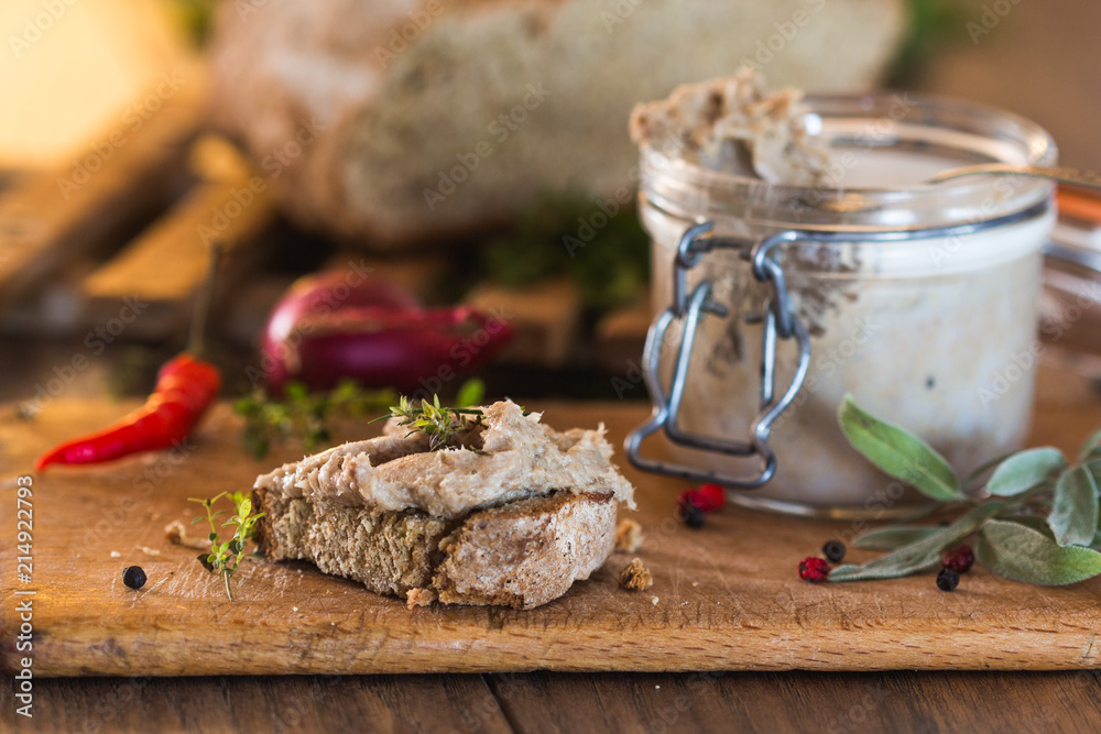 Rustic pâté\pate made from pork liver in a glass jar and a slice of ...