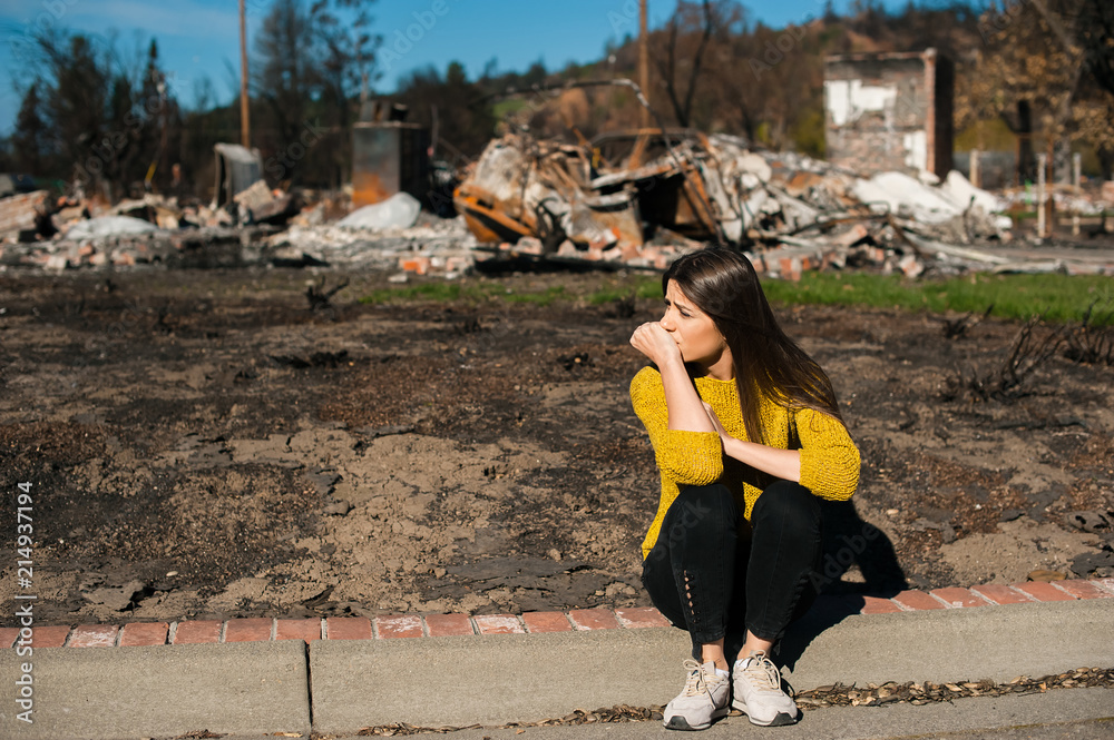 Sad woman home owner holds his head by hand checking burnt out house ...
