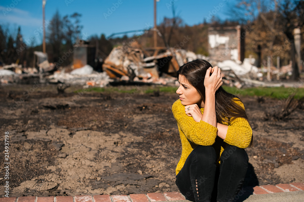 Sad woman home owner holds his head by hand checking burnt out house ...