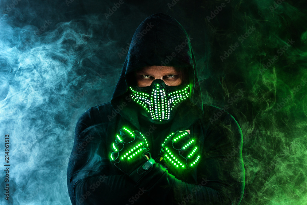 Mysterious man in black wear, neon mask and gloves. Character pastor or ...