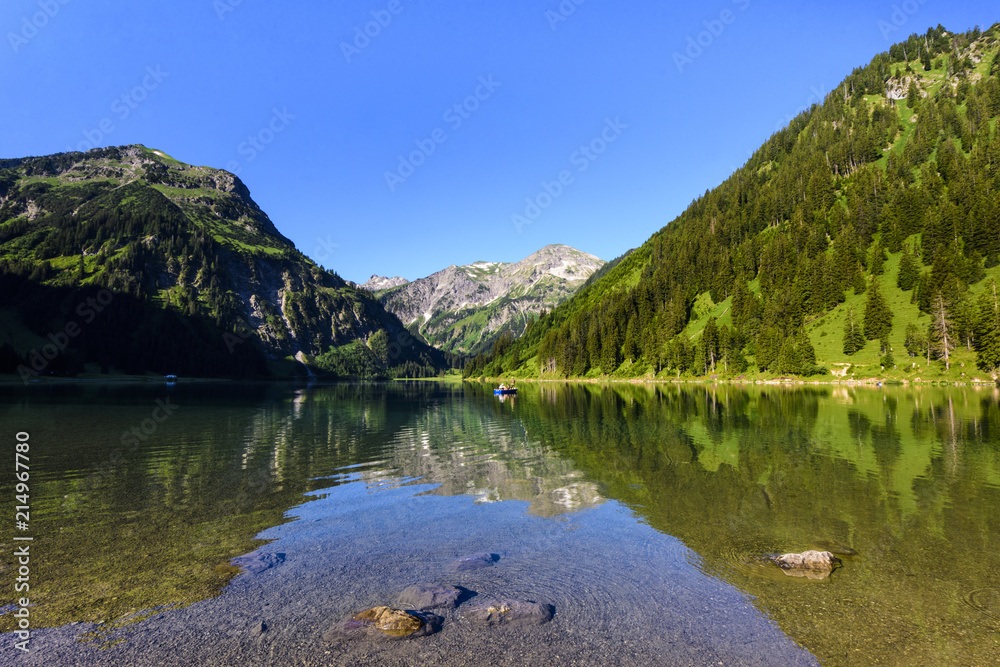 Symmetrical reflections of mountain range and boat in the clear water ...