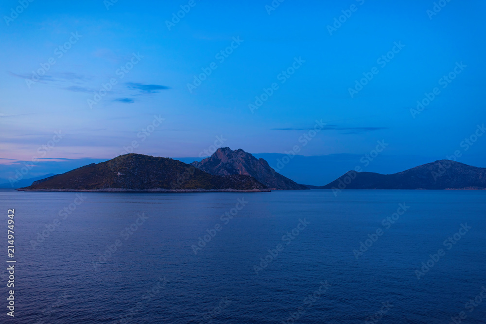 View of the Greek island of Atokos from the ferry at sunset. Greek ...