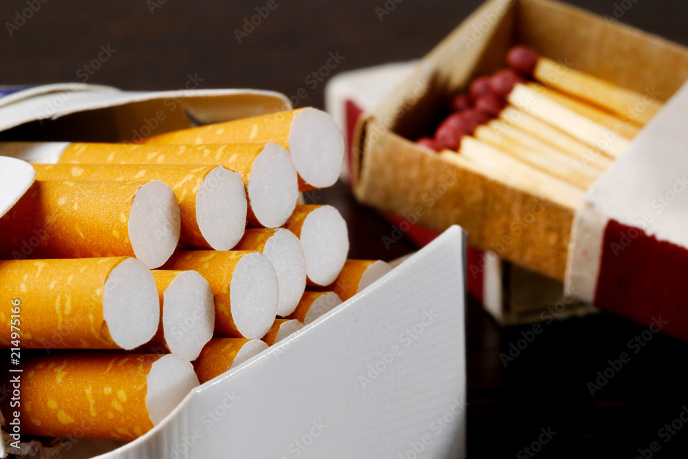 closeup of open pack of cigarettes and box of matches on background ...