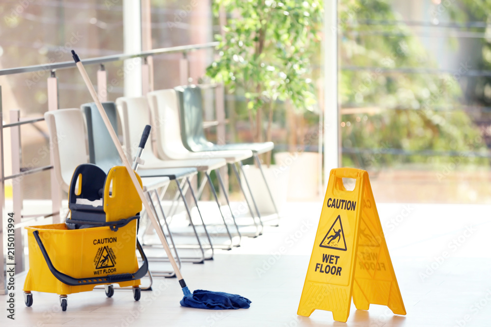 Safety sign with phrase Caution wet floor and mop bucket, indoors ...