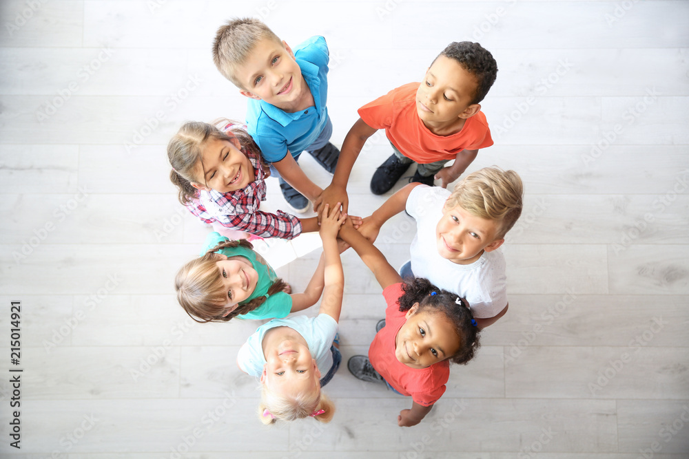 Little children putting their hands together indoors, top view. Unity ...