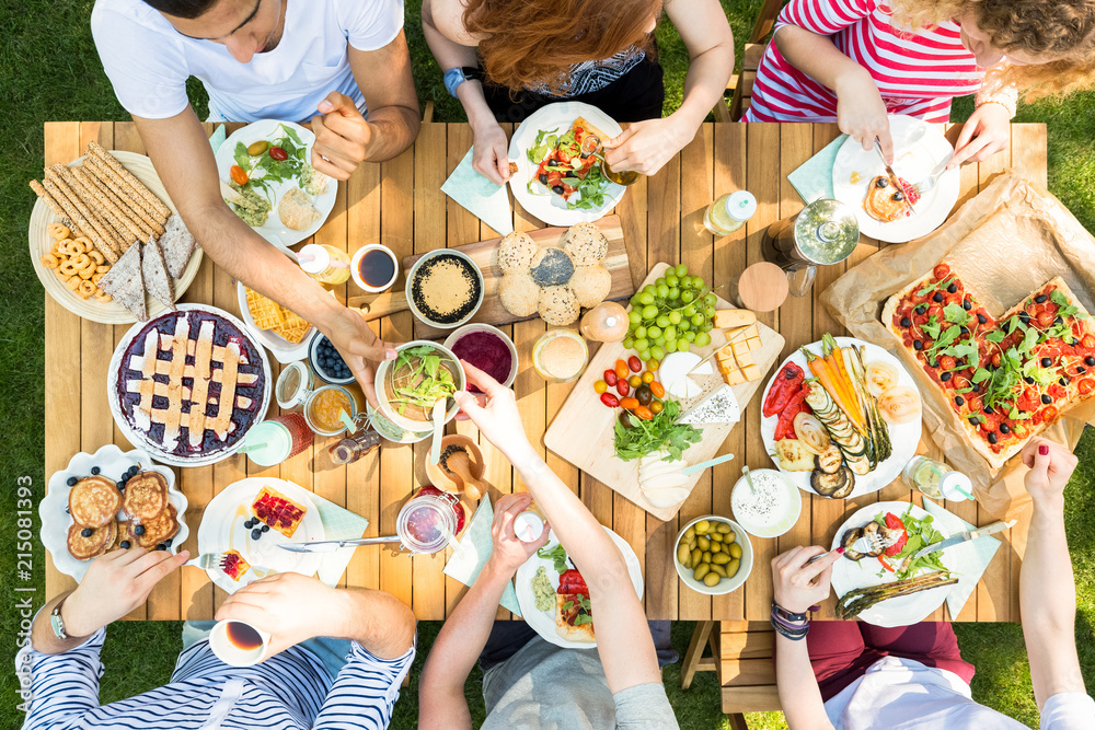 Top view on table with pizza, pastry and fruits. People eating lunch ...