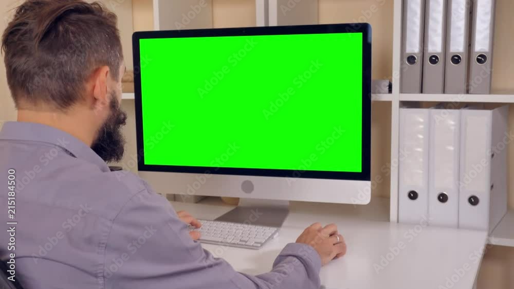 man sitting at workplace paying game on computer in small office ...