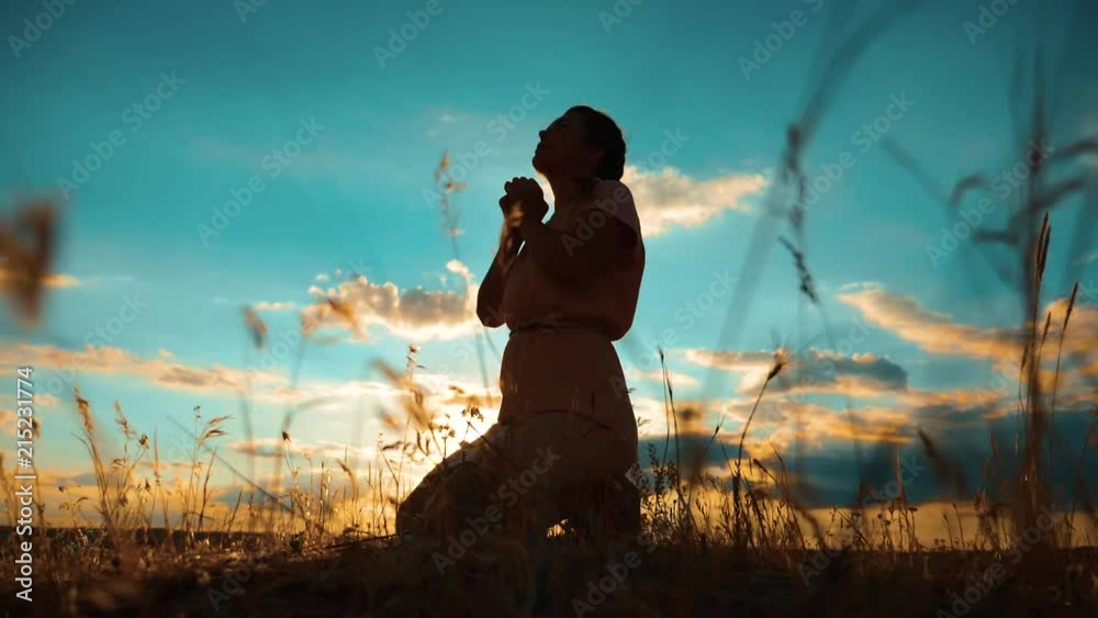 woman praying on her knees. Girl folded her hands in prayer silhouette ...