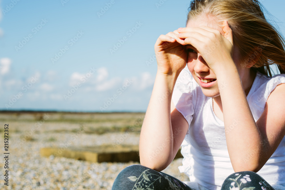 Foto de Tween girl outdoors sheltering her eyes from the sun as she ...