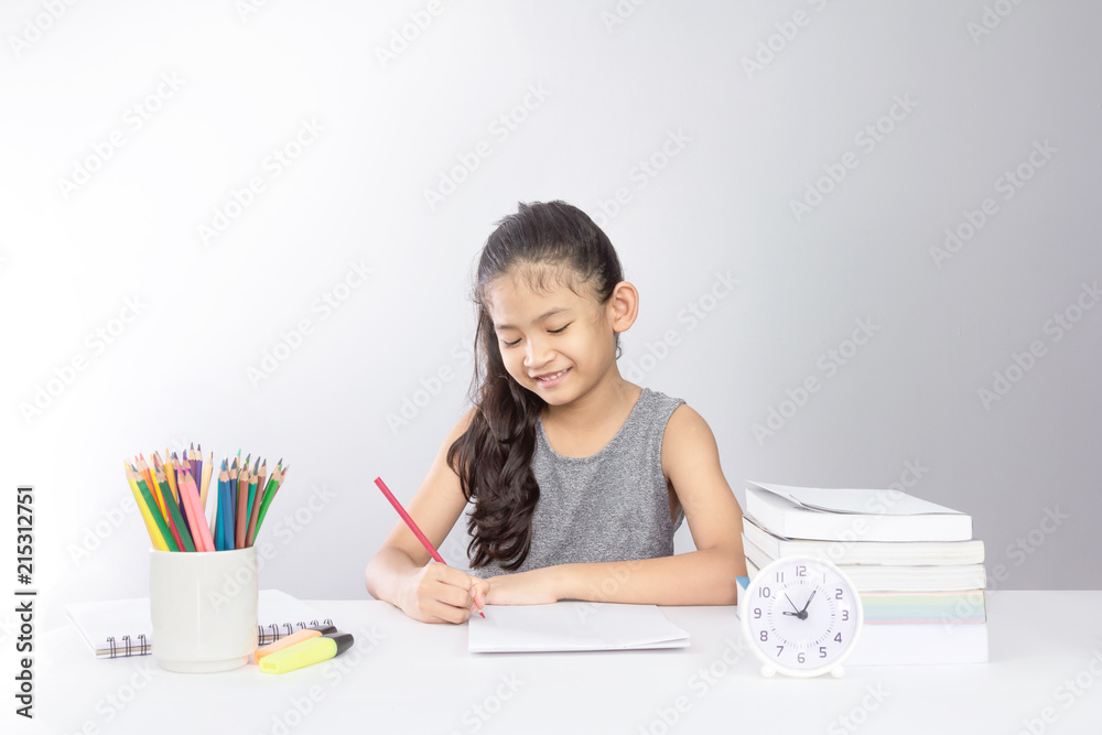 Little asian kid doing homework or drawing at home with smling face ...