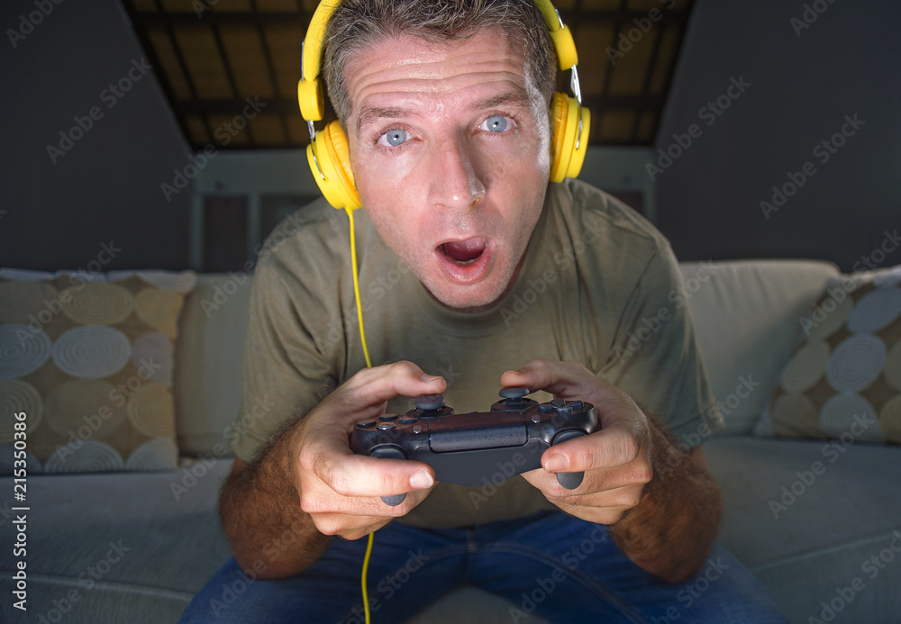 lifestyle portrait of young happy and excited gamer man with headphones ...