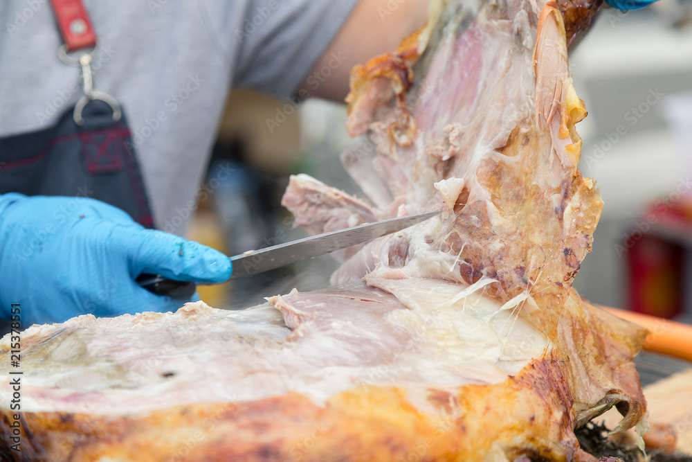 Cutting the mutton hulk fried on a grill for the Uzbek pilaf. Male ...