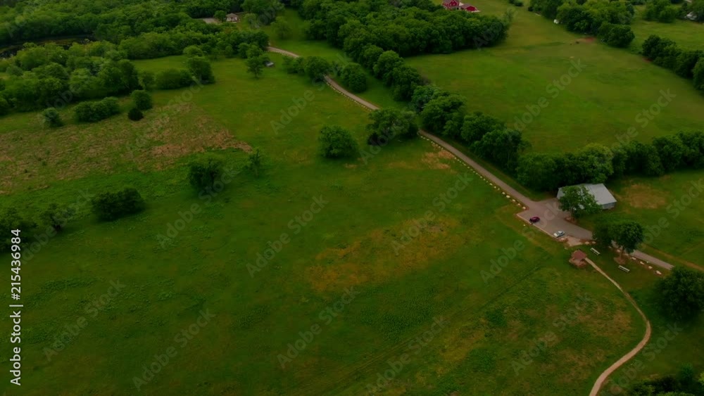 This shot of an open Praire with a dirt trail beside a growth of trees ...