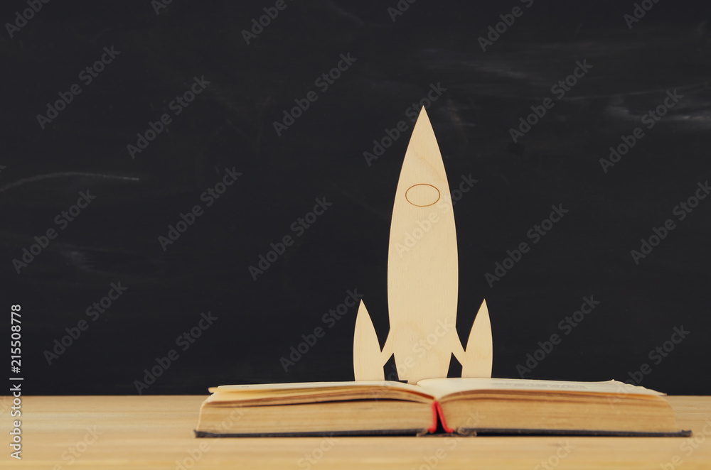 Back to school concept. wooden rocket over open book in front of ...