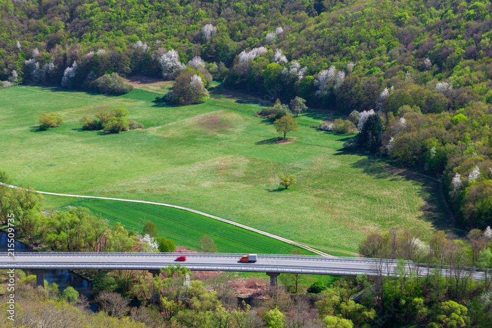 Straße mit Autos durch grüne bewaldete Landschaft Stock-Foto | Adobe Stock