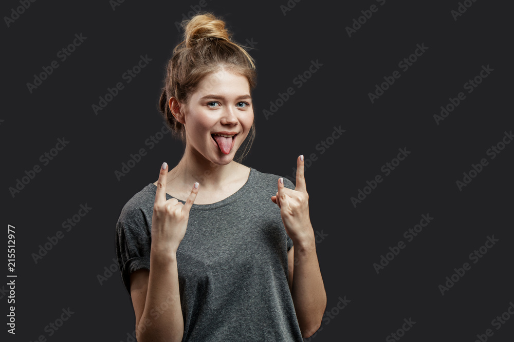Rock and roll Joyful young woman looking at camera and gesturing rock ...