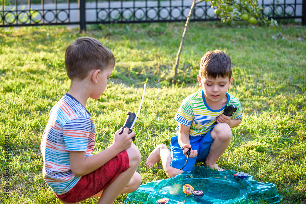 Two boys playing with a Beyblade, spinning top kid toy. Popular ...