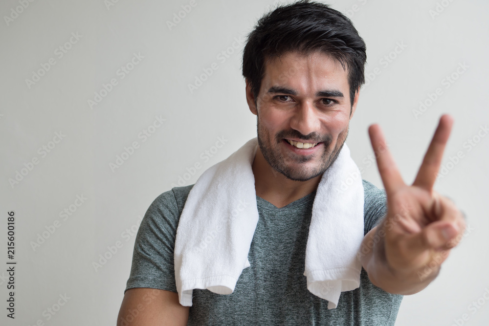 confident fitness man pointing up two fingers; portrait of happy ...