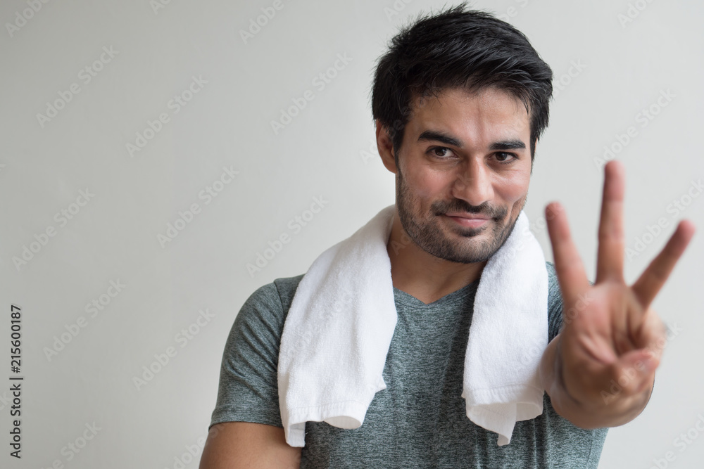 confident fitness man pointing up three finger; portrait of happy ...