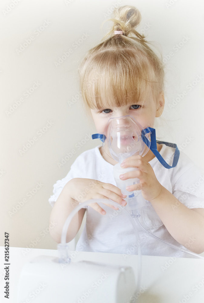 Little girl in a mask for inhalations, making inhalation with nebulizer ...