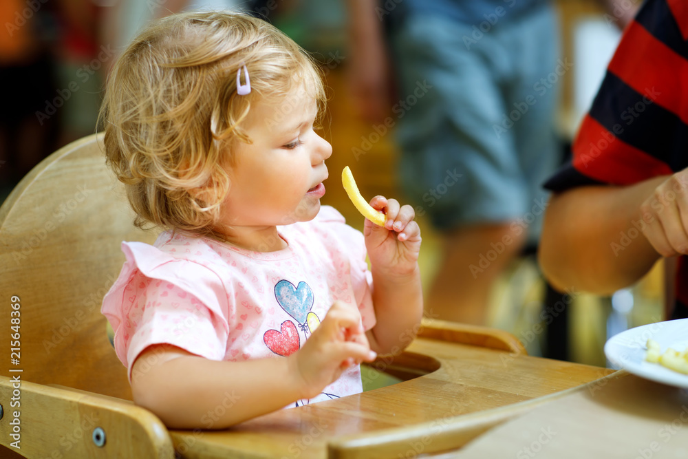 Adorable toddler girl eating healthy vegetables and unhealthy french ...