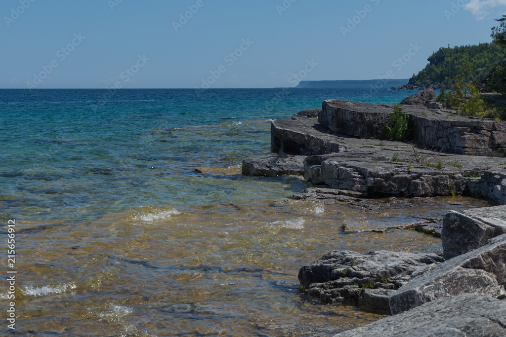 Lake Huron shoreline blue green water and limestone rocks along the ...