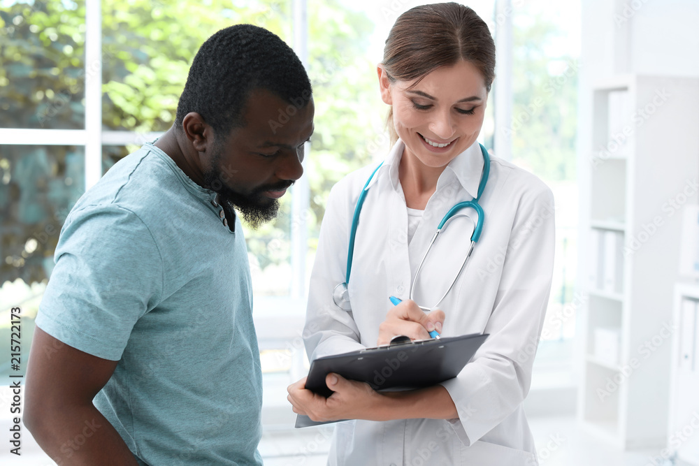 Young doctor consulting African-American patient in hospital Stock ...