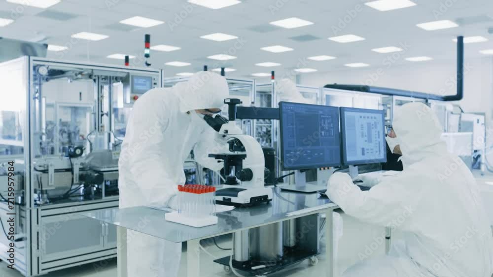 Team of Research Scientists in Sterile Suits Working with Computers ...