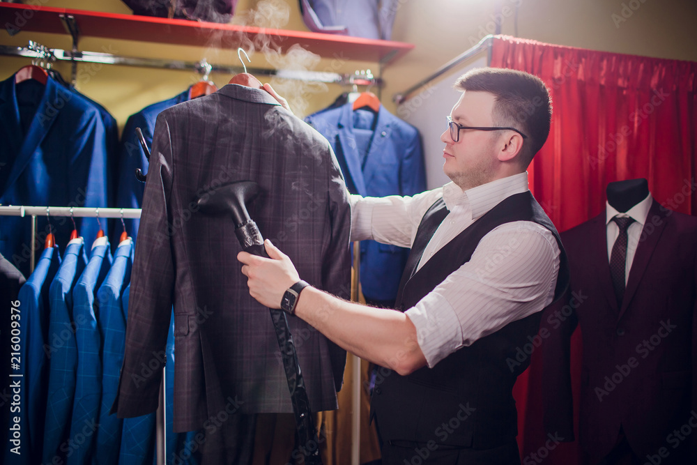 tailor cuts and sews a suit. A young man in the tailoring shop makes ...
