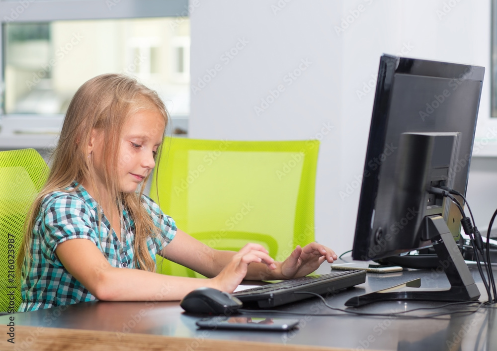 Little girl 7 years old works behind a computer. Online education ...