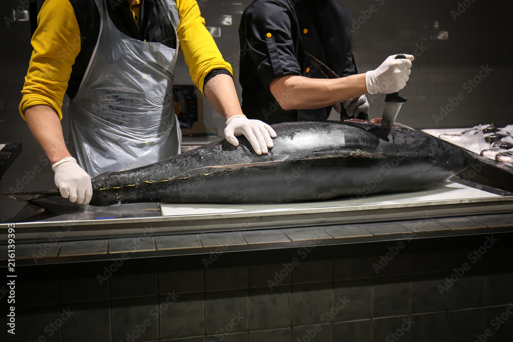 Men working with fresh tuna at table in fish market Stock Photo | Adobe ...