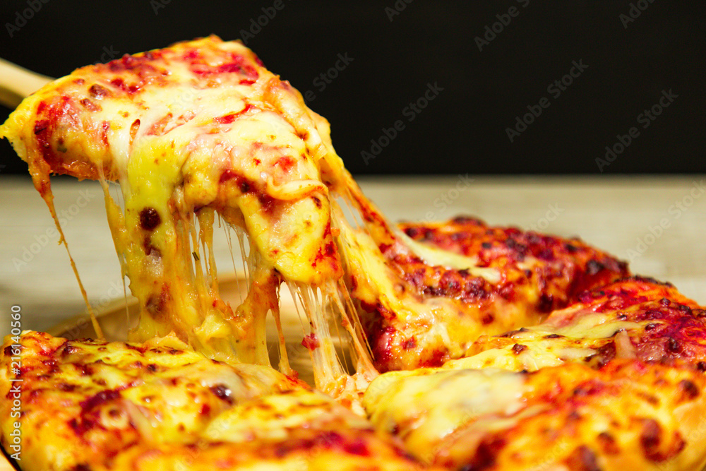 Very cheesy pizza slice in hand.Hot pizza slice with melting cheese on ...
