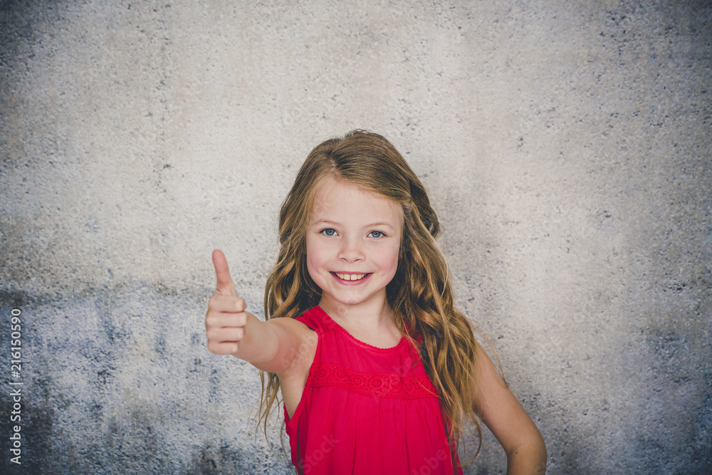 beautiful girl in red shirt in front of concrete background is posing ...