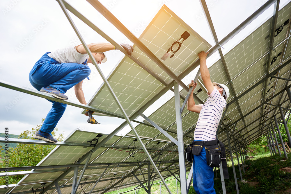 Installing of solar photo voltaic panel system. Two technicians lifting ...