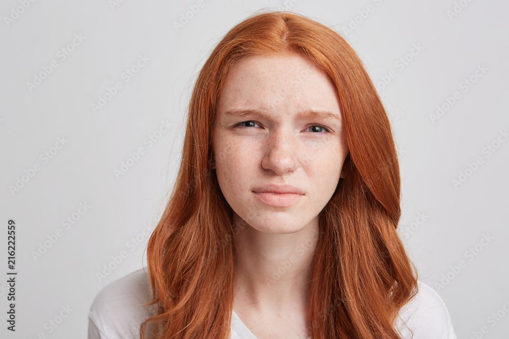 Portrait of sad unhappy young woman with long wavy red hair and ...