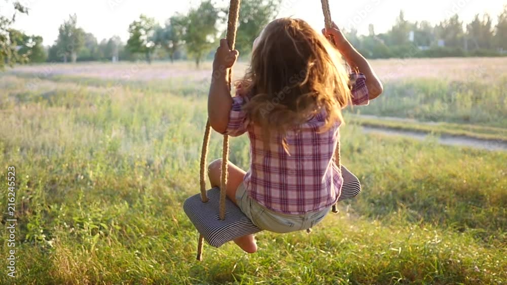 Happy cute little child girl have fun sway spin on a swing on nature ...