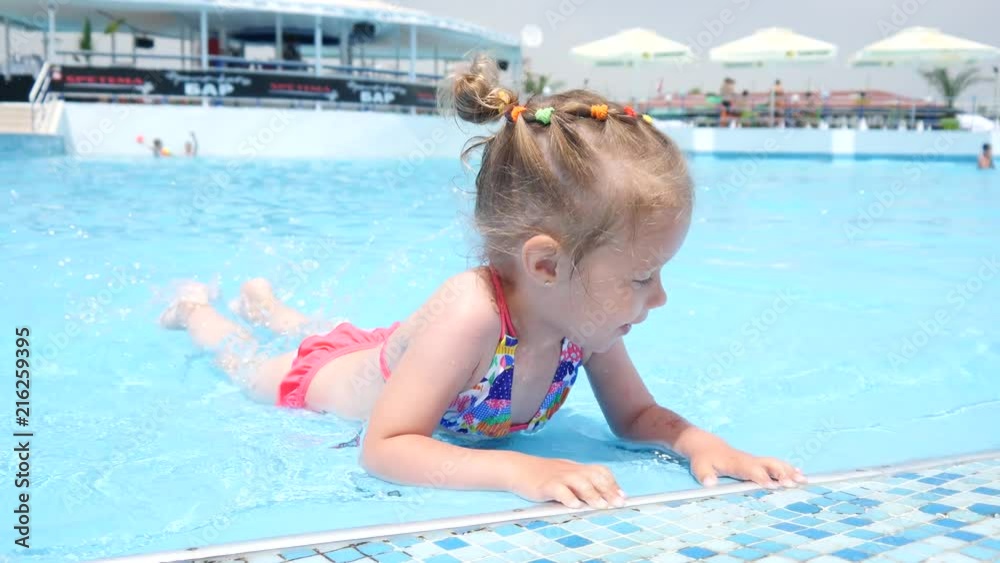 Cute little child girl have fun swim in swimming pool water at summer ...
