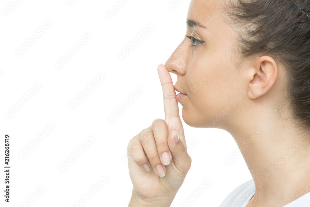 Secretive young woman placing finger on lips asking shh, quiet, silence ...