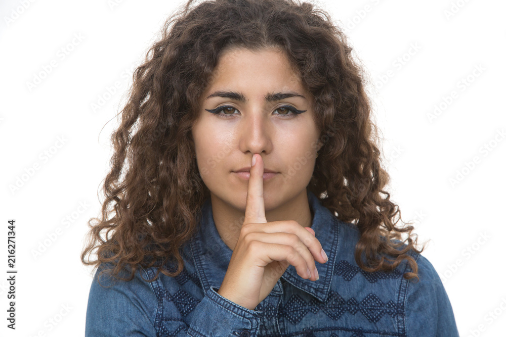 Secretive young woman placing finger on lips asking shh, quiet, silence ...