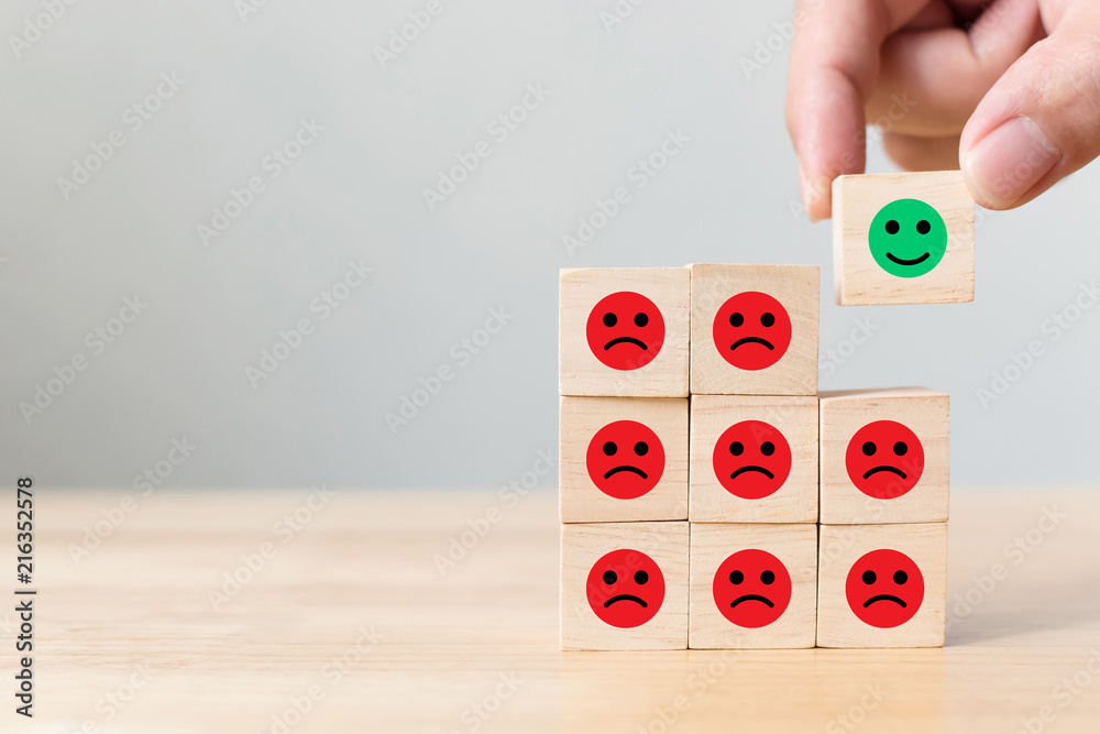 Hand picked wooden block with icon face emotion happiness and sadness ...